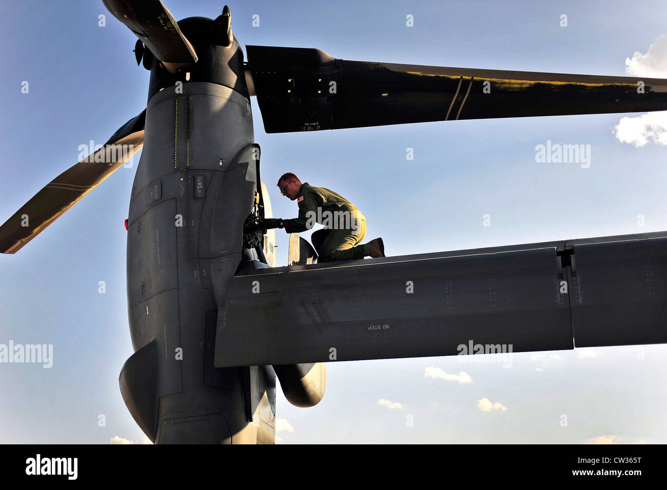 A US Air Force flight engineer inspects one of the tilt-rotors on a CV ...