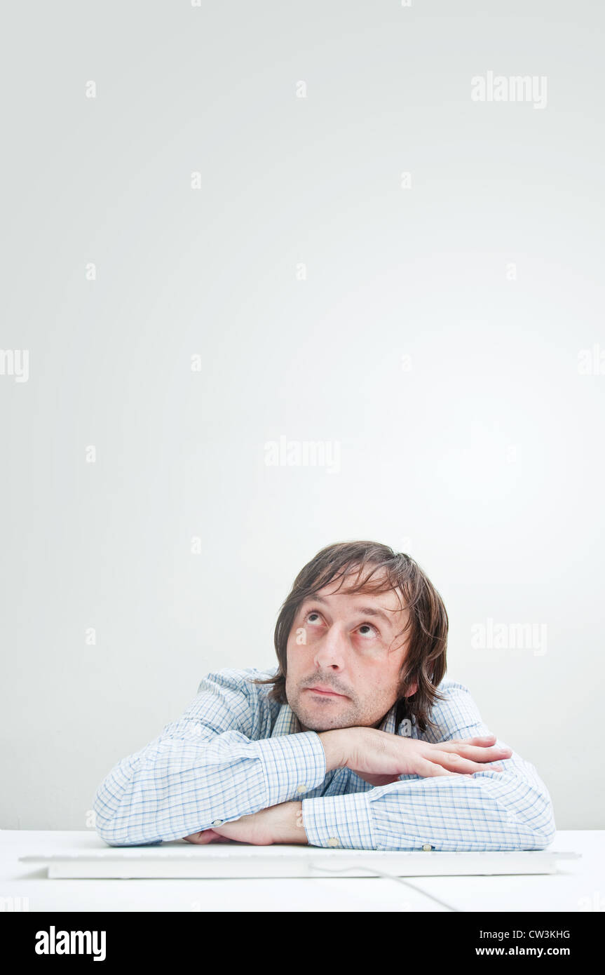 Businessman sitting at the table and thinking, with thought balloon ...