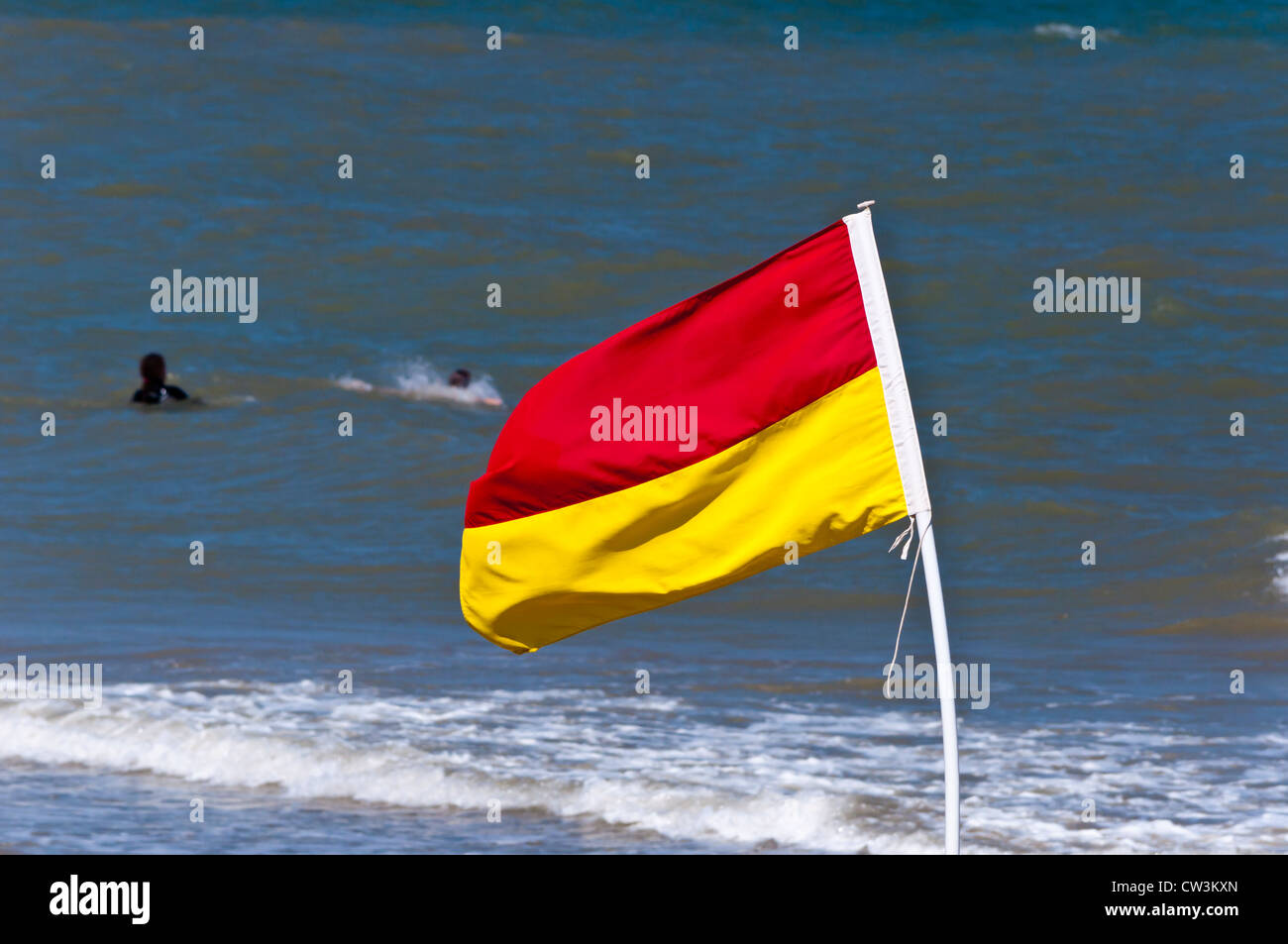Red and yellow lifeguard flag with swimmers Stock Photo - Alamy