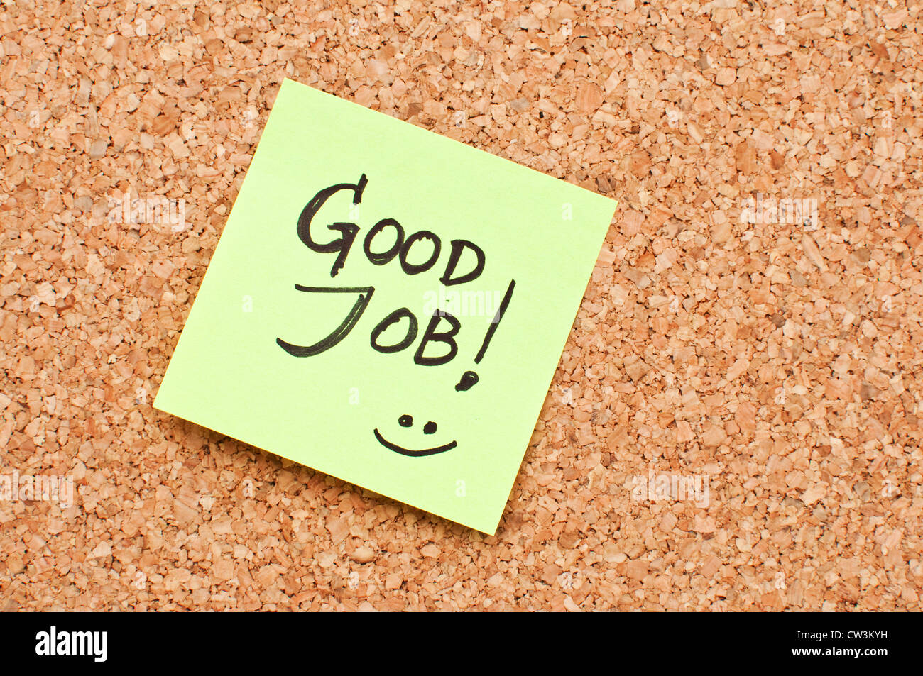 Yellow sticky note on an office cork bulletin board with Good job ...