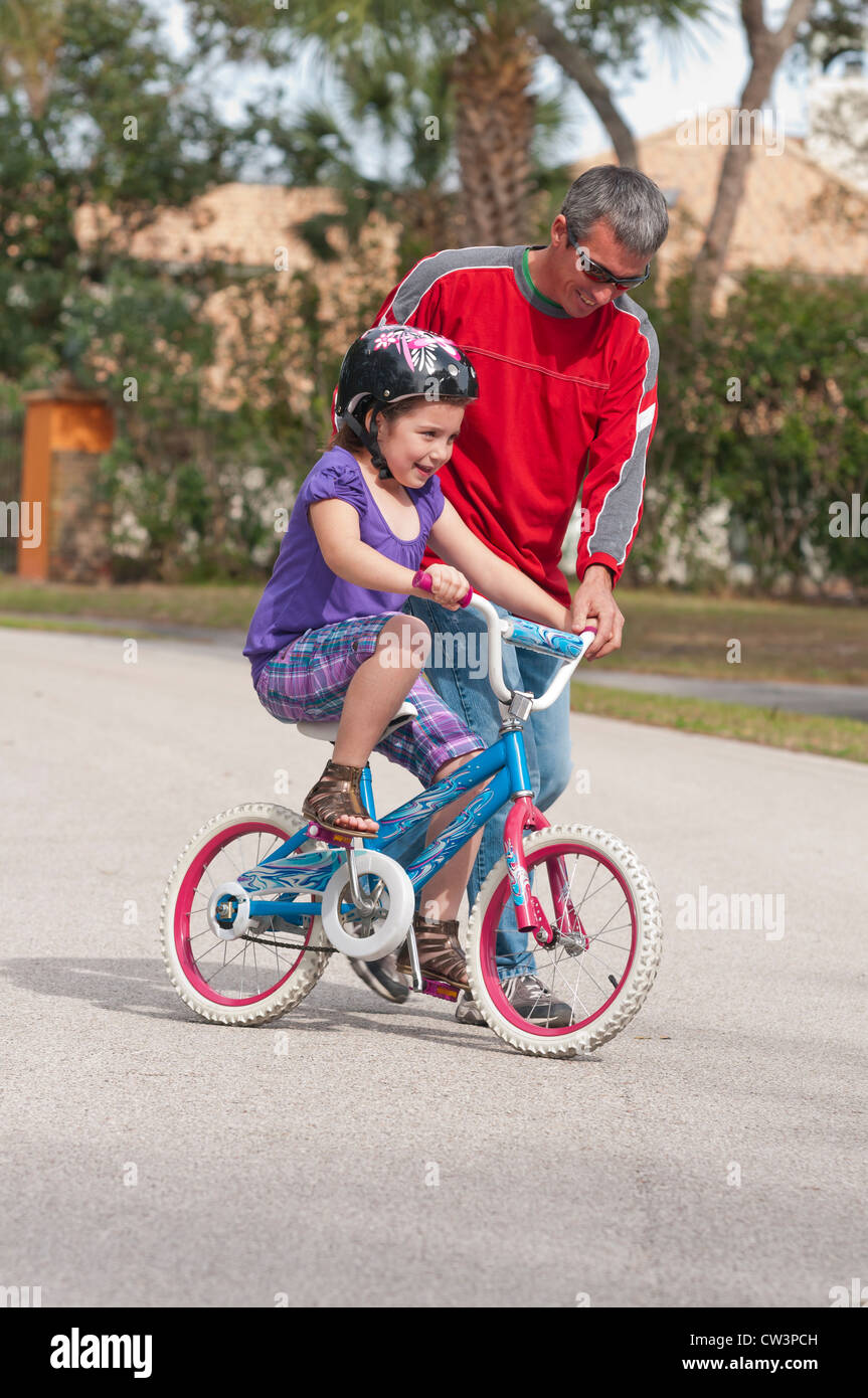Dad and daughter learning to ride a bicycle safely Stock Photo - Alamy