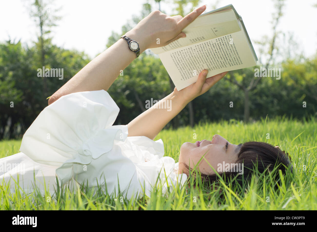 Beautiful young woman reading a book on nature Stock Photo - Alamy
