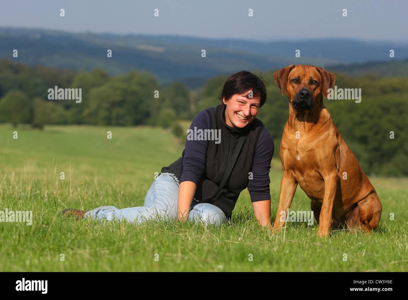 Rhodesian Ridgeback (Canis lupus familiaris) and woman owner sitting in ...