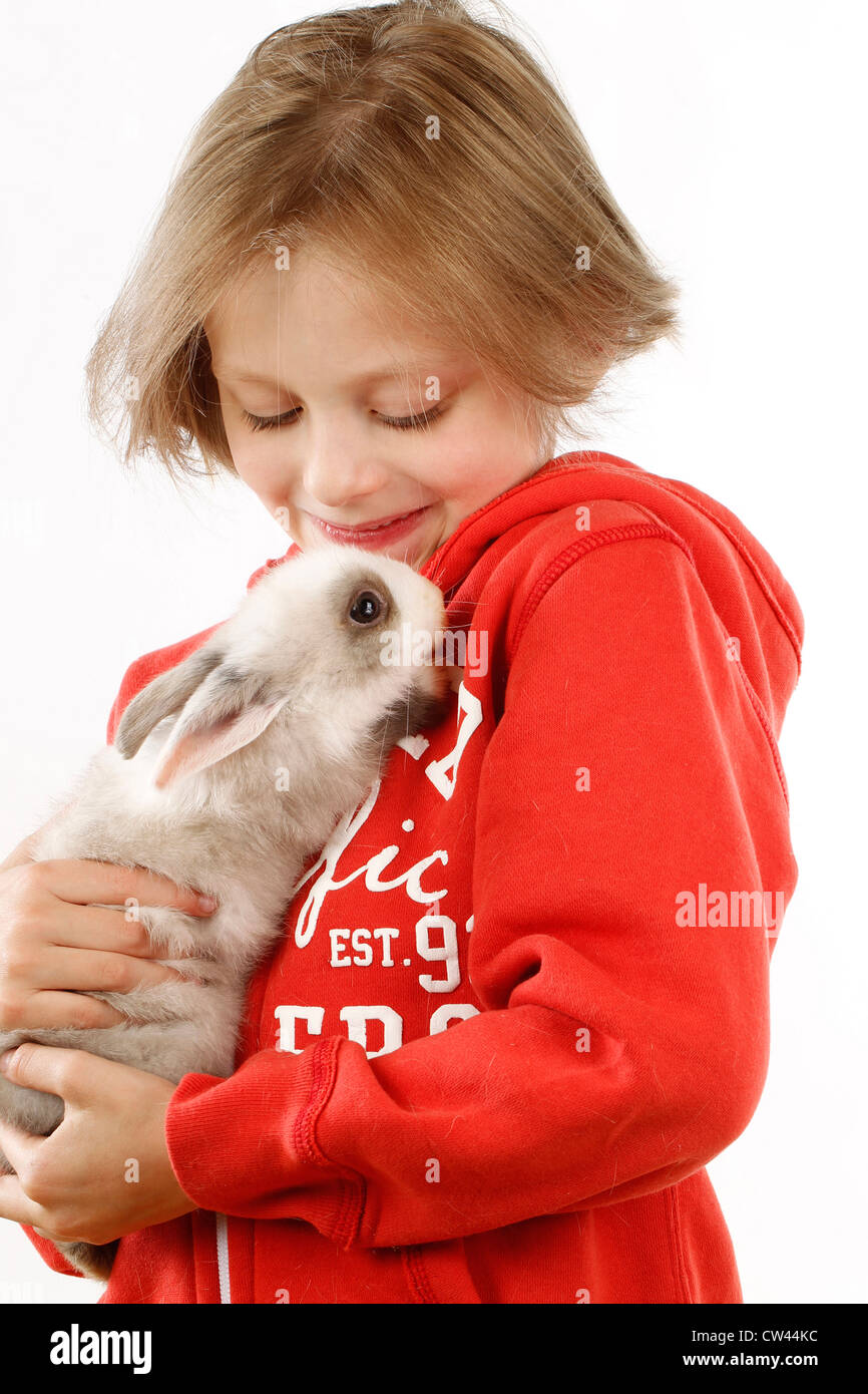 Smiling child holding a pet rabbit. Studio picture against a white ...