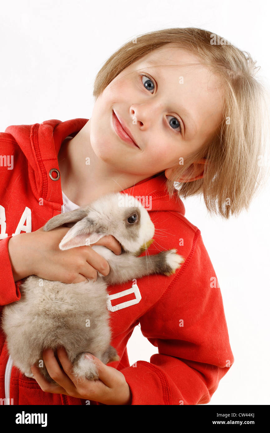 Smiling child holding a pet rabbit. Studio picture against a white ...