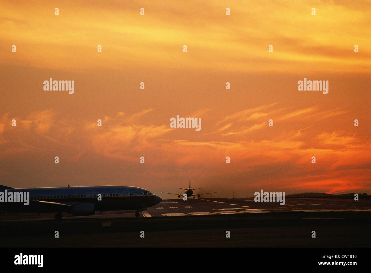 Airplanes on runway at sunset Stock Photo - Alamy