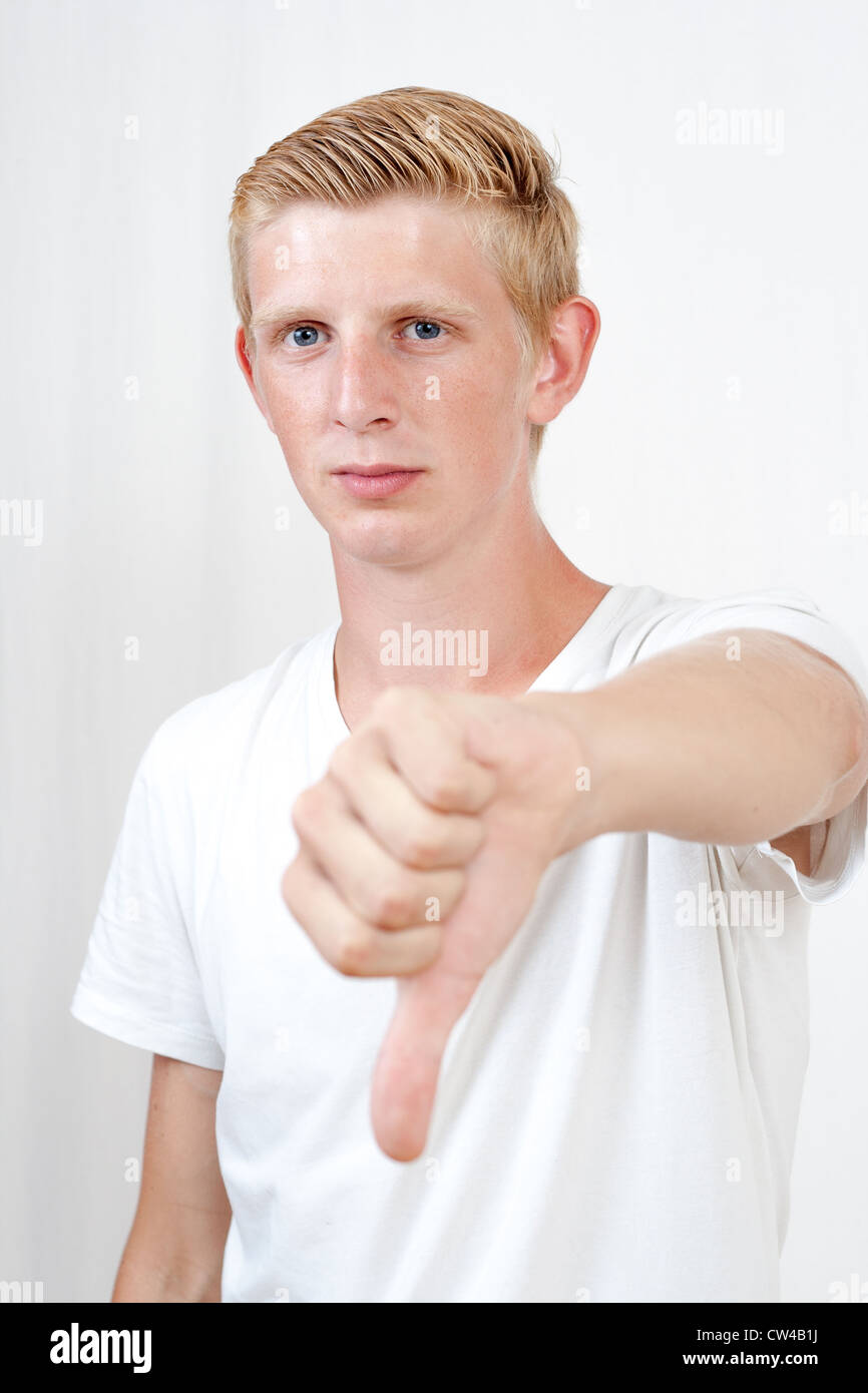 young man with blue eyes gives the thumbs down gesture on grey ...