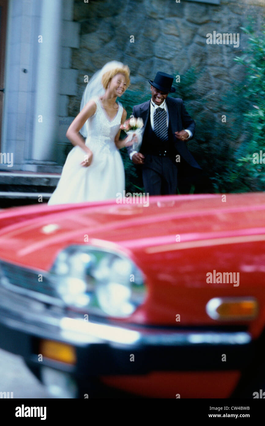 Newlywed couple running towards a car Stock Photo - Alamy
