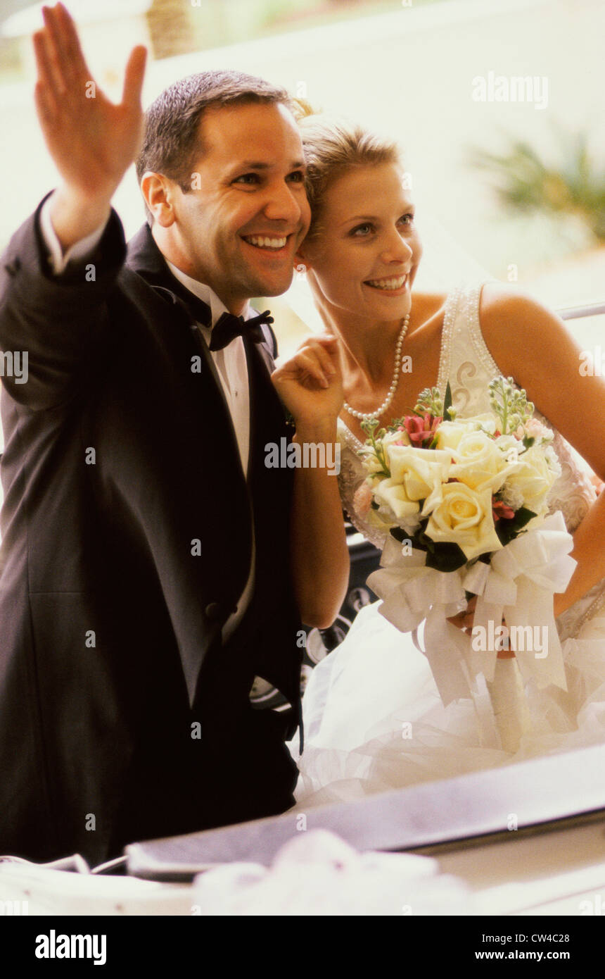 Newlywed couple waving from a convertible car Stock Photo - Alamy