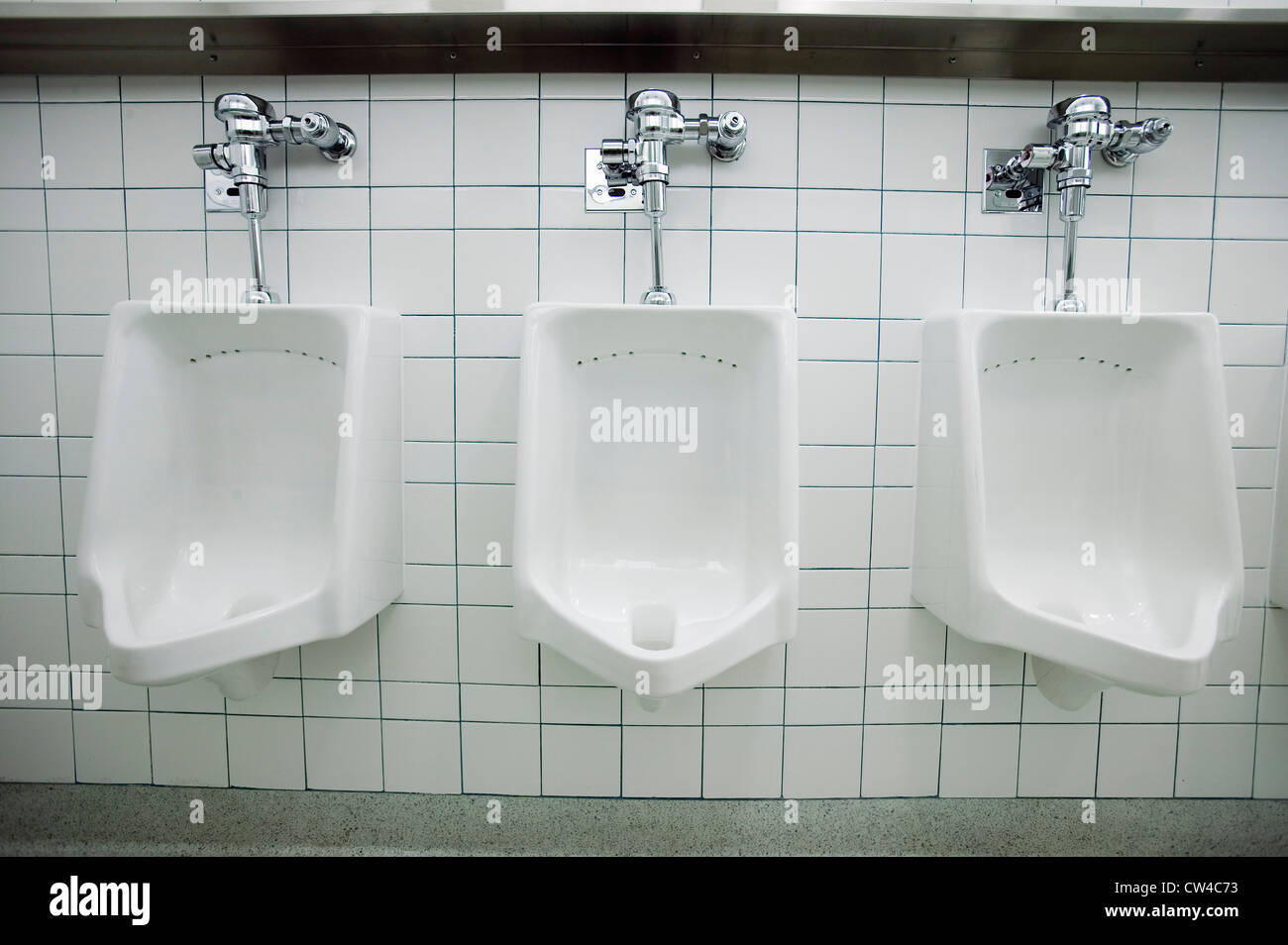 Three white urinals in men's bathroom Stock Photo - Alamy