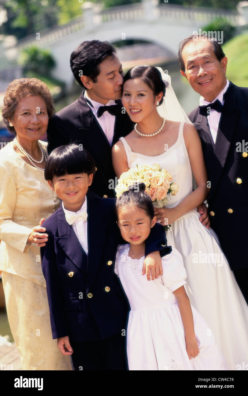 Portrait of a newlywed couple standing with their parents Stock Photo ...