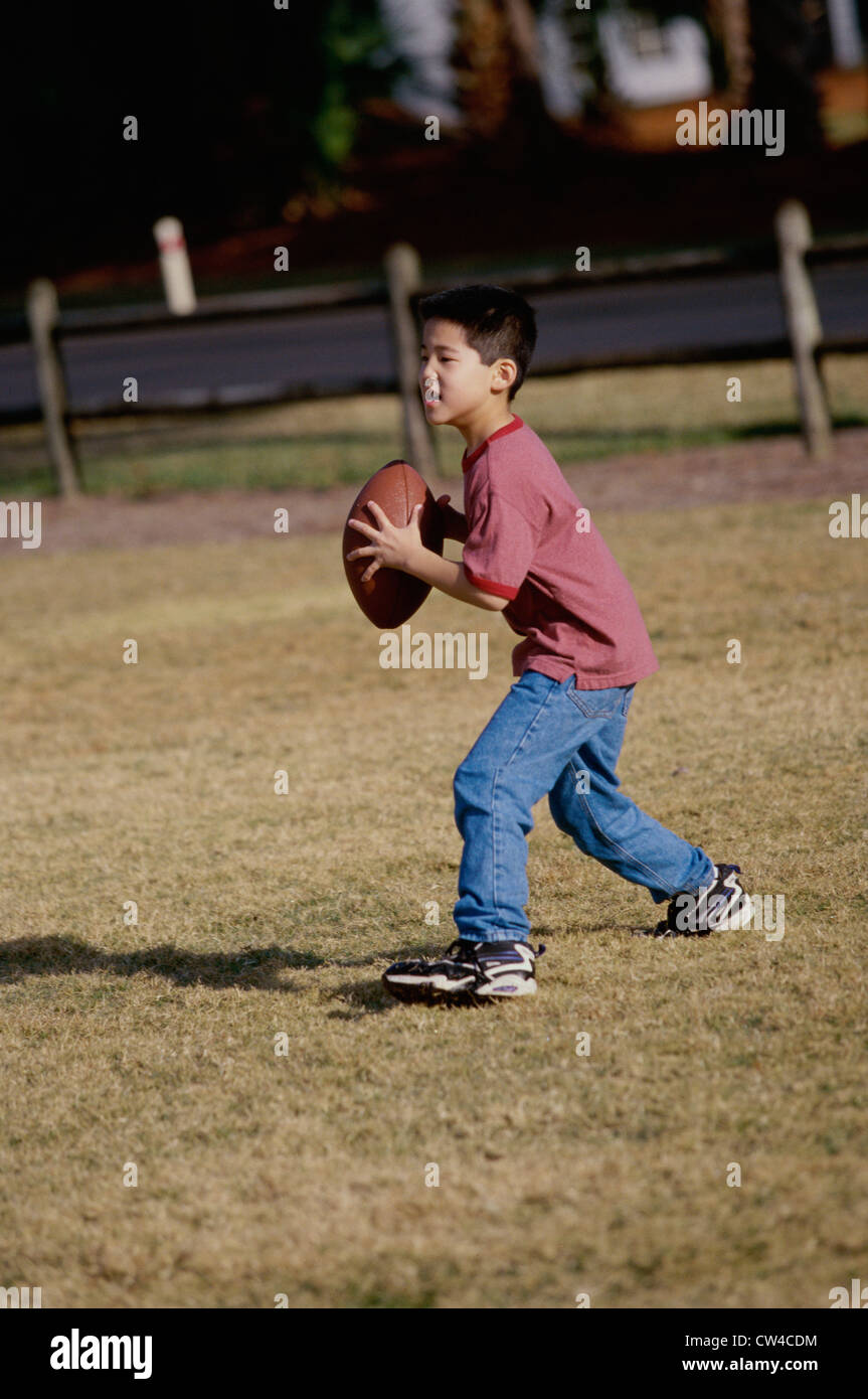 Boy playing with a rugby ball Stock Photo - Alamy