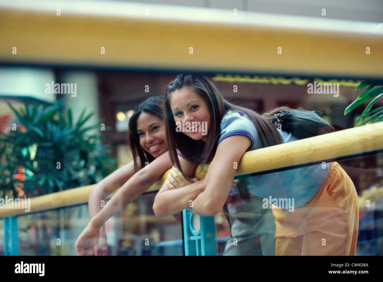 Two teenage girls leaning over a railing Stock Photo - Alamy