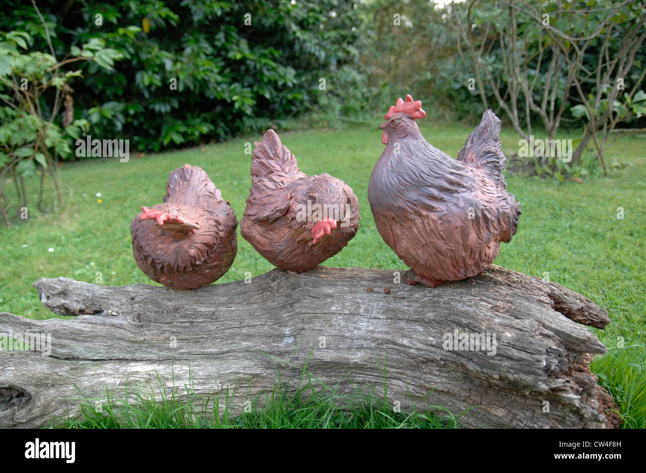 Ceramic chickens on a log Stock Photo - Alamy