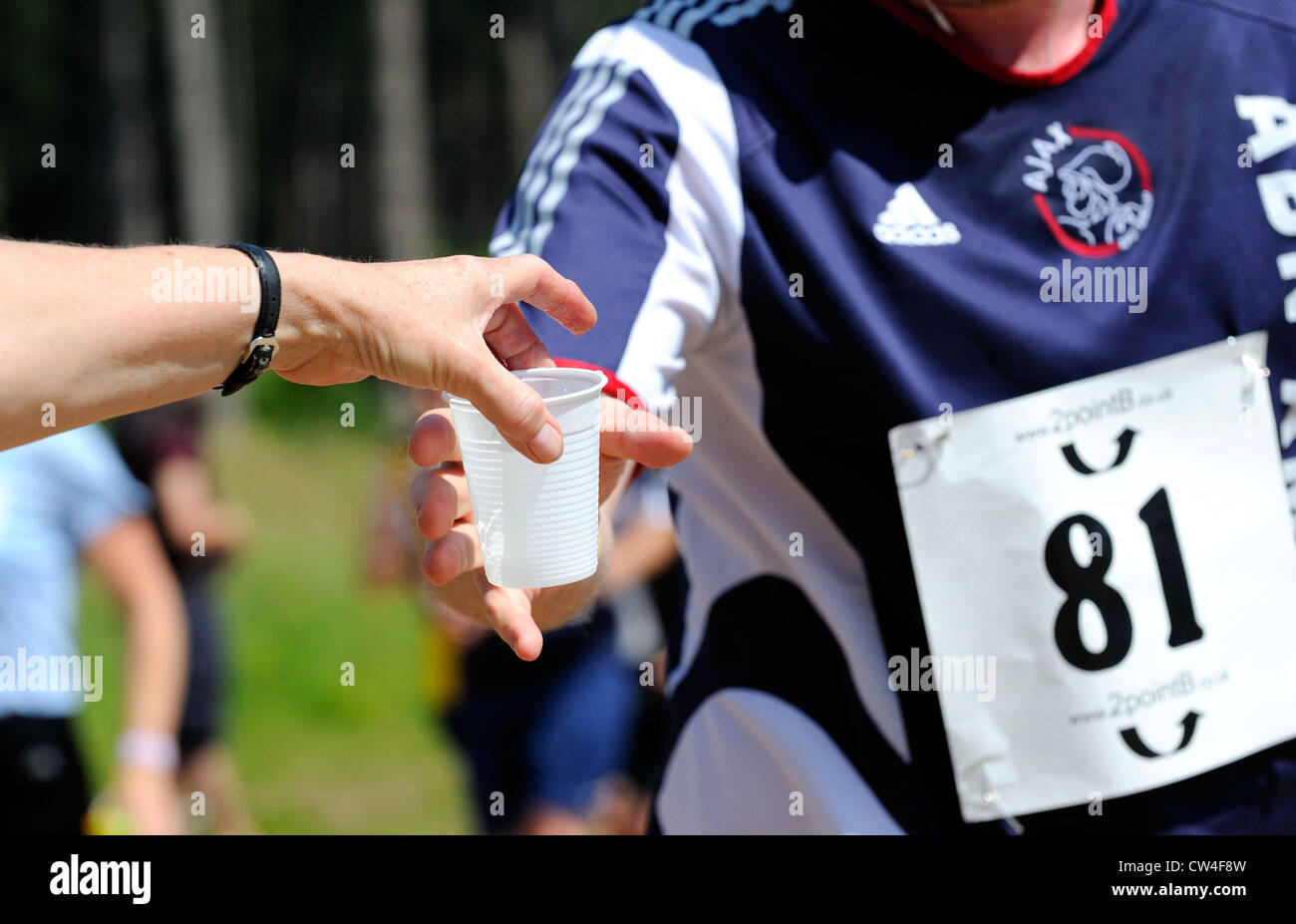 Runners taking on cold refreshments of water during a hot summers day ...