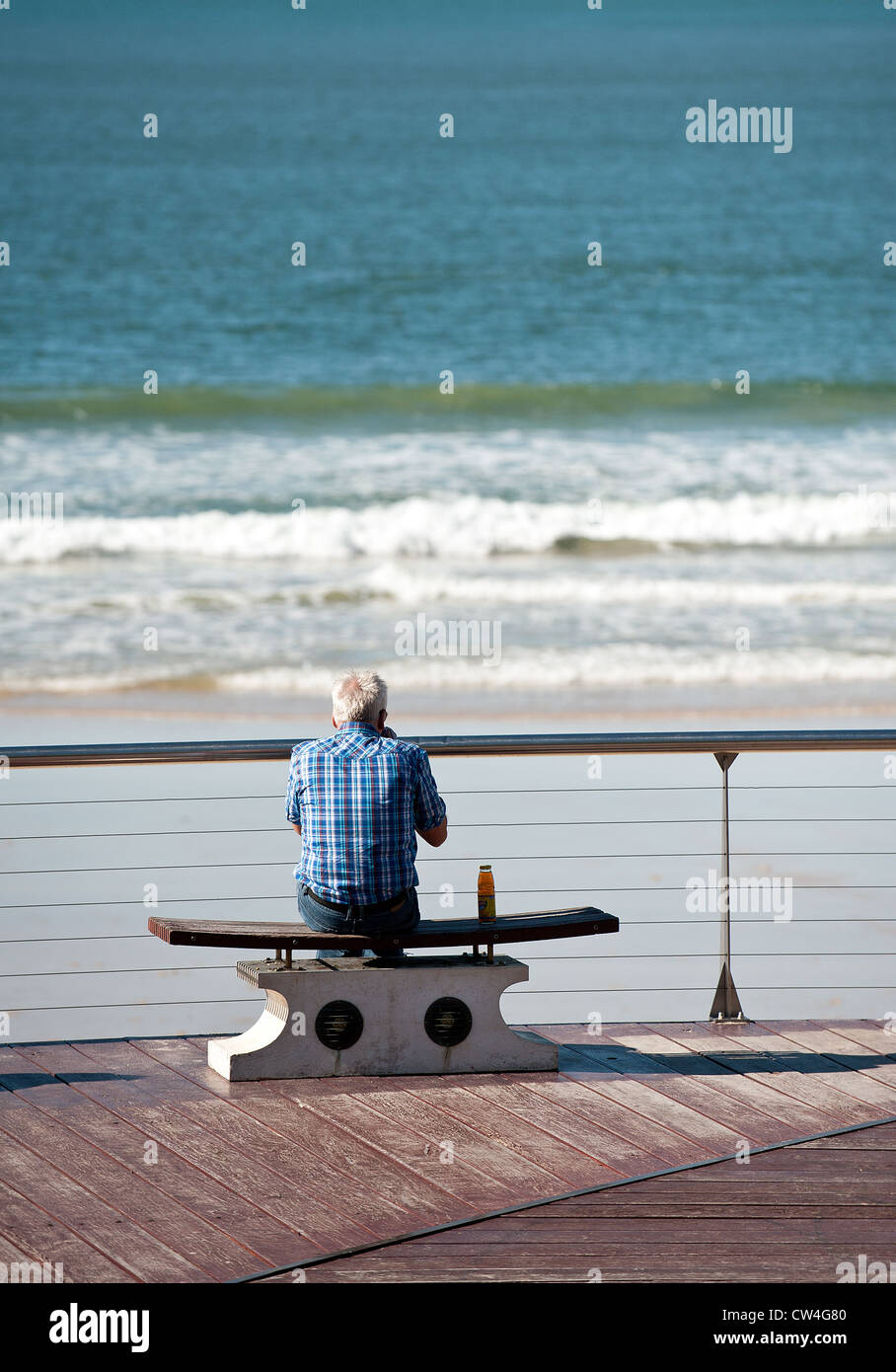 A man sitting on a bench on the Mooloolaba boardwalk on the Sunshine ...