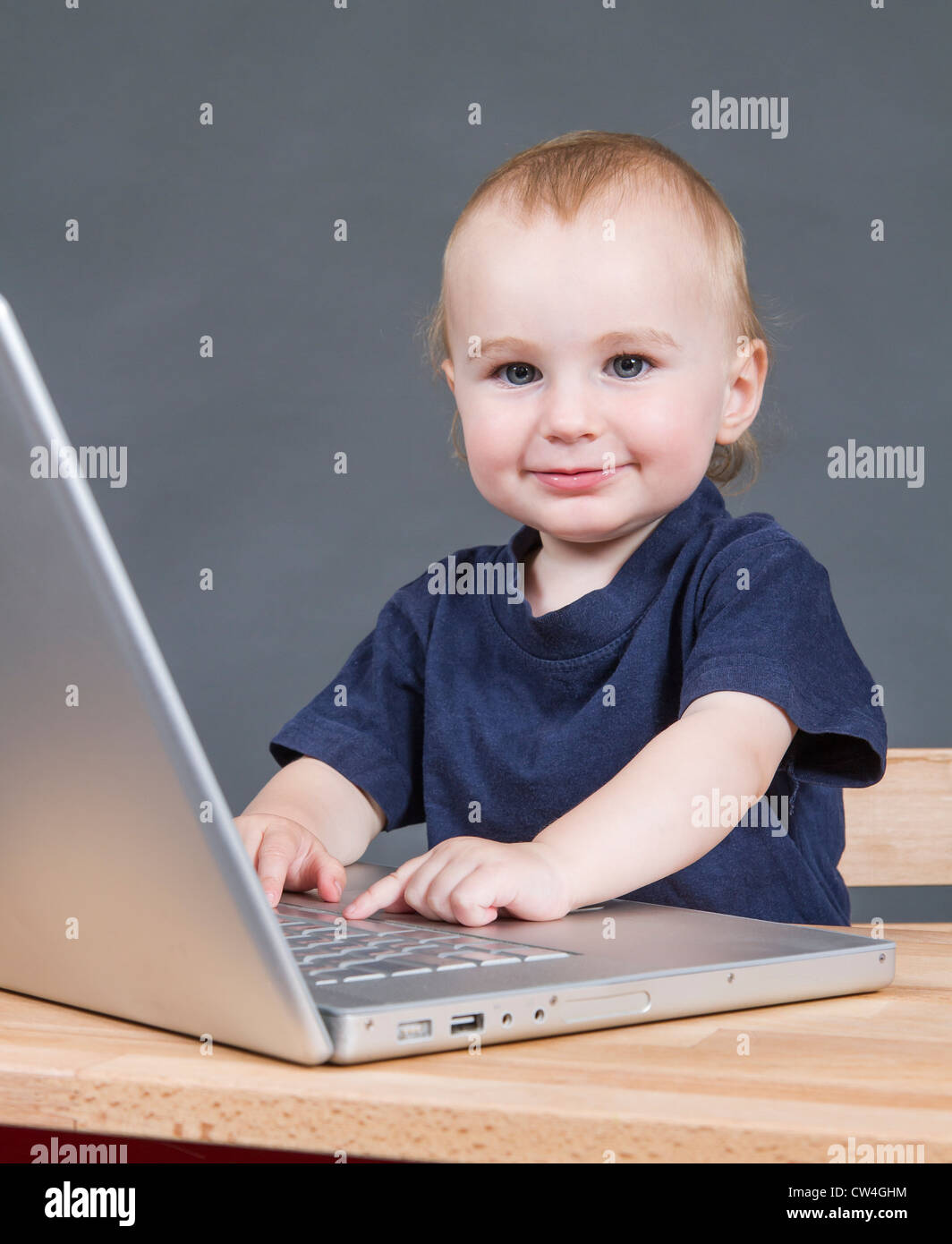 young child with laptop computer on wooden desk in grey background ...