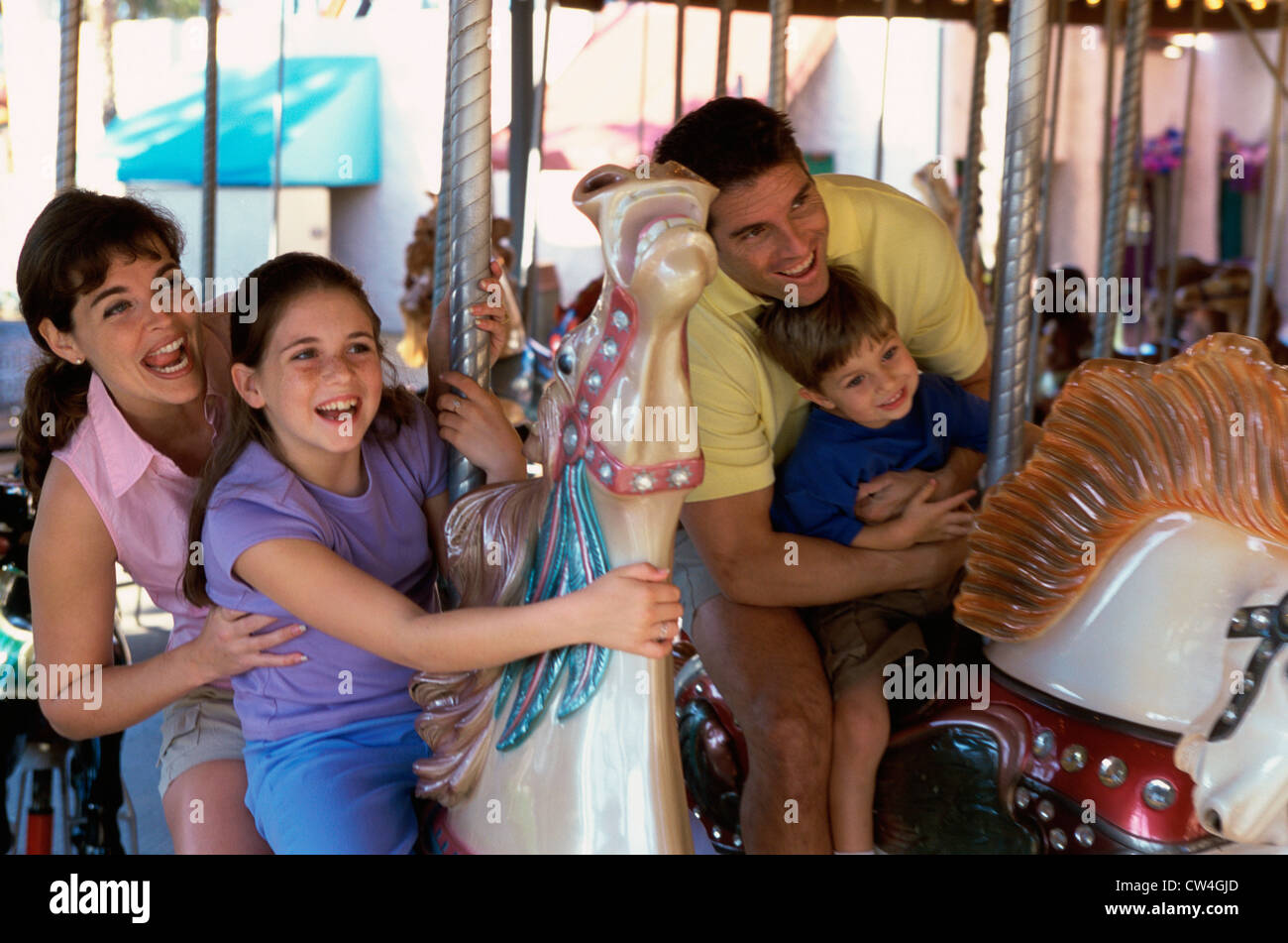 Parents with their son and daughter riding on carousel horses Stock ...
