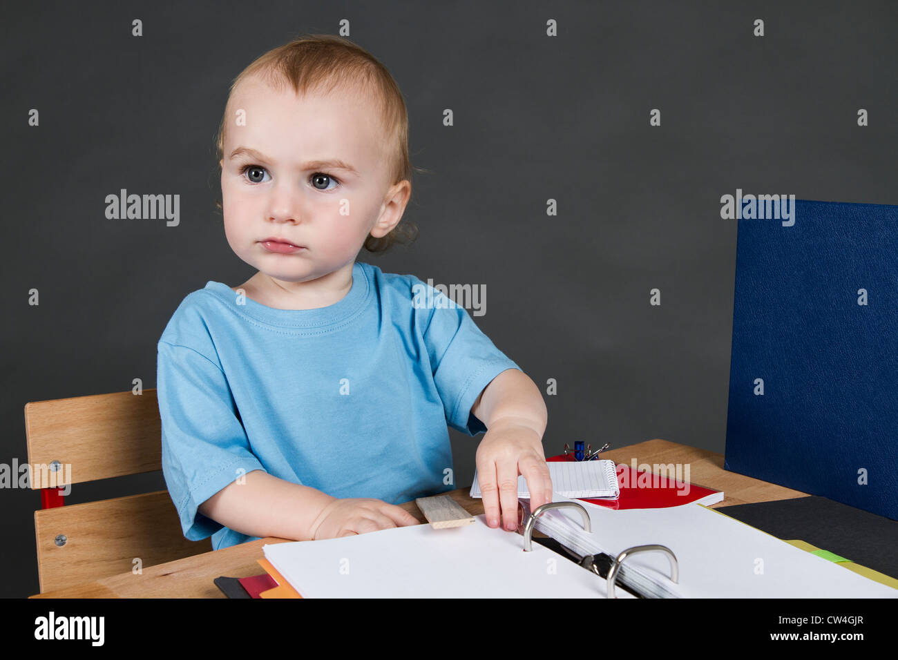 young child at small desk in grey background Stock Photo - Alamy