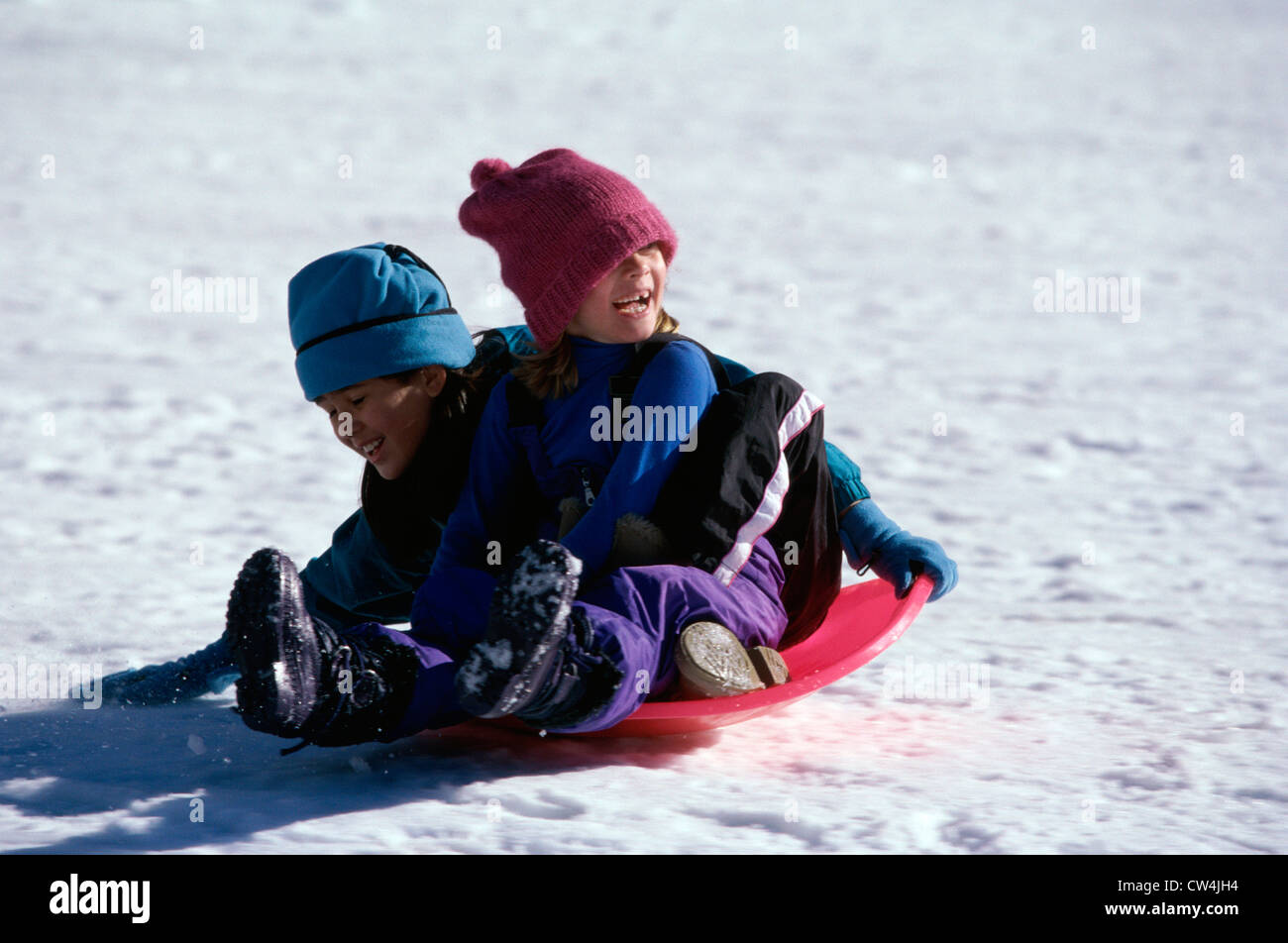 Two girls riding on a sled Stock Photo - Alamy