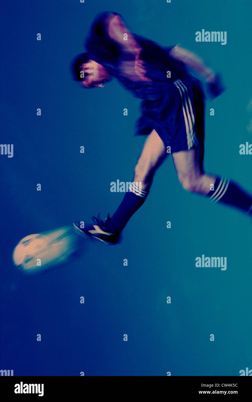 Side profile of a soccer player in mid-air kicking a soccer ball Stock ...