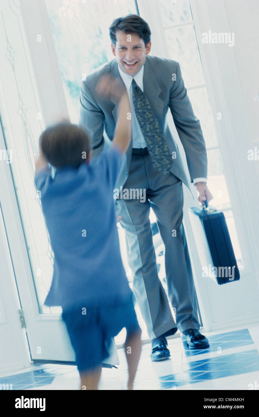 Boy running to greet his father at the front door Stock Photo - Alamy