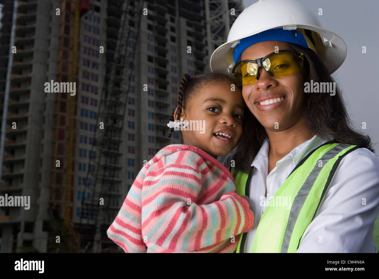 Female architect holding her daughter in front of a building under ...
