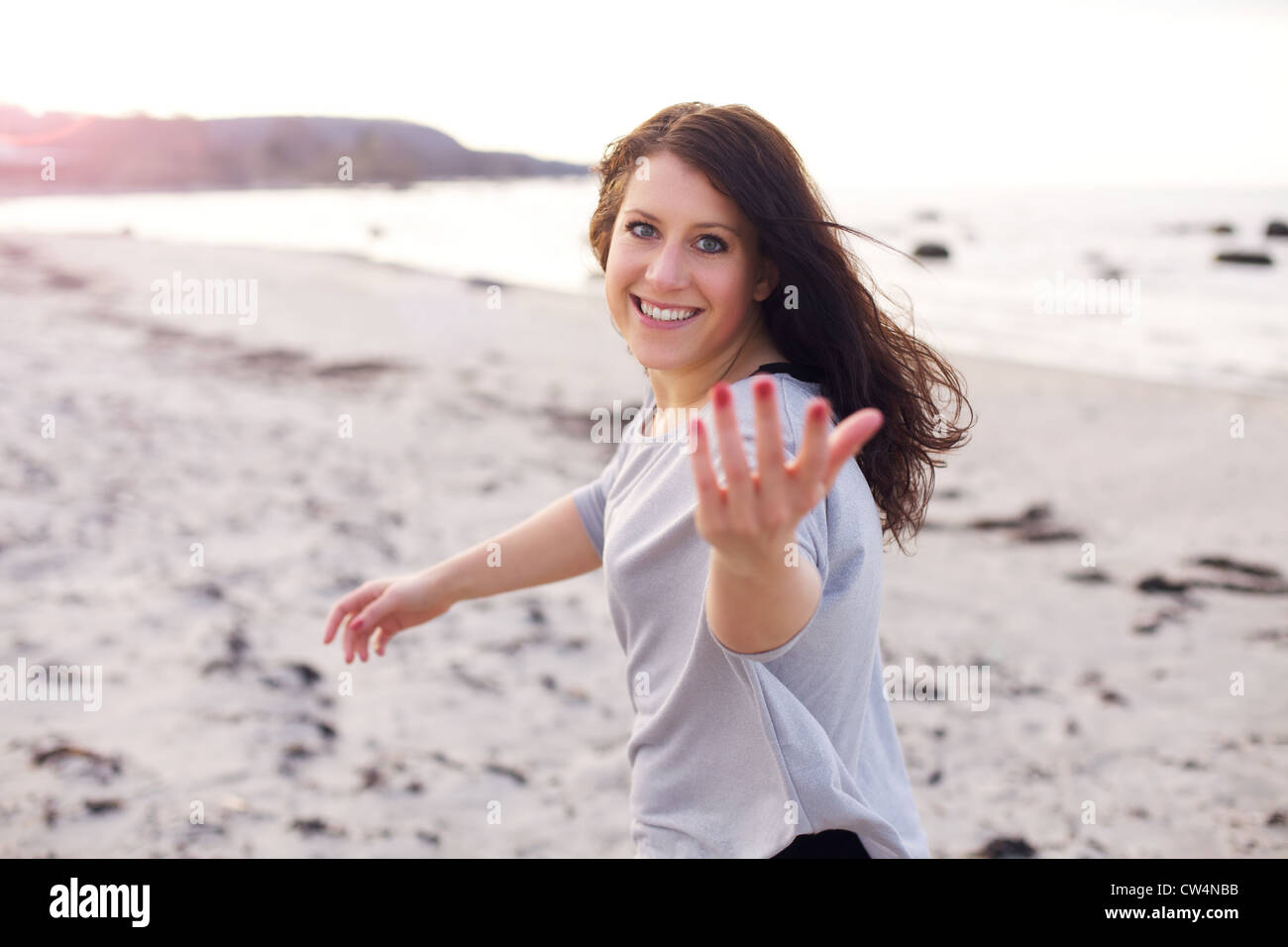 Cheerful woman inviting you to run with her along the sandy shore Stock ...