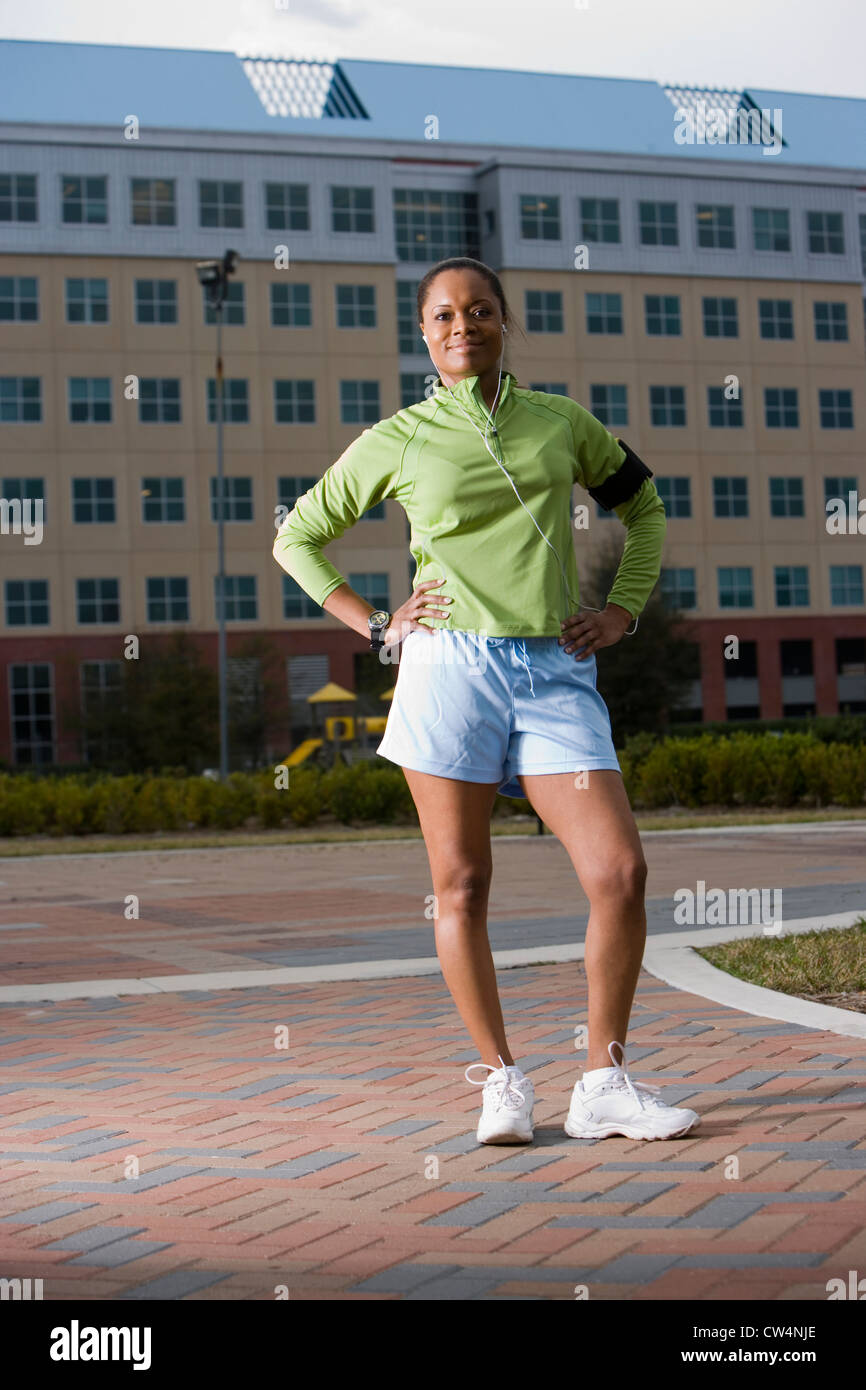 Portrait of young woman in sports clothing standing on walkway with ...
