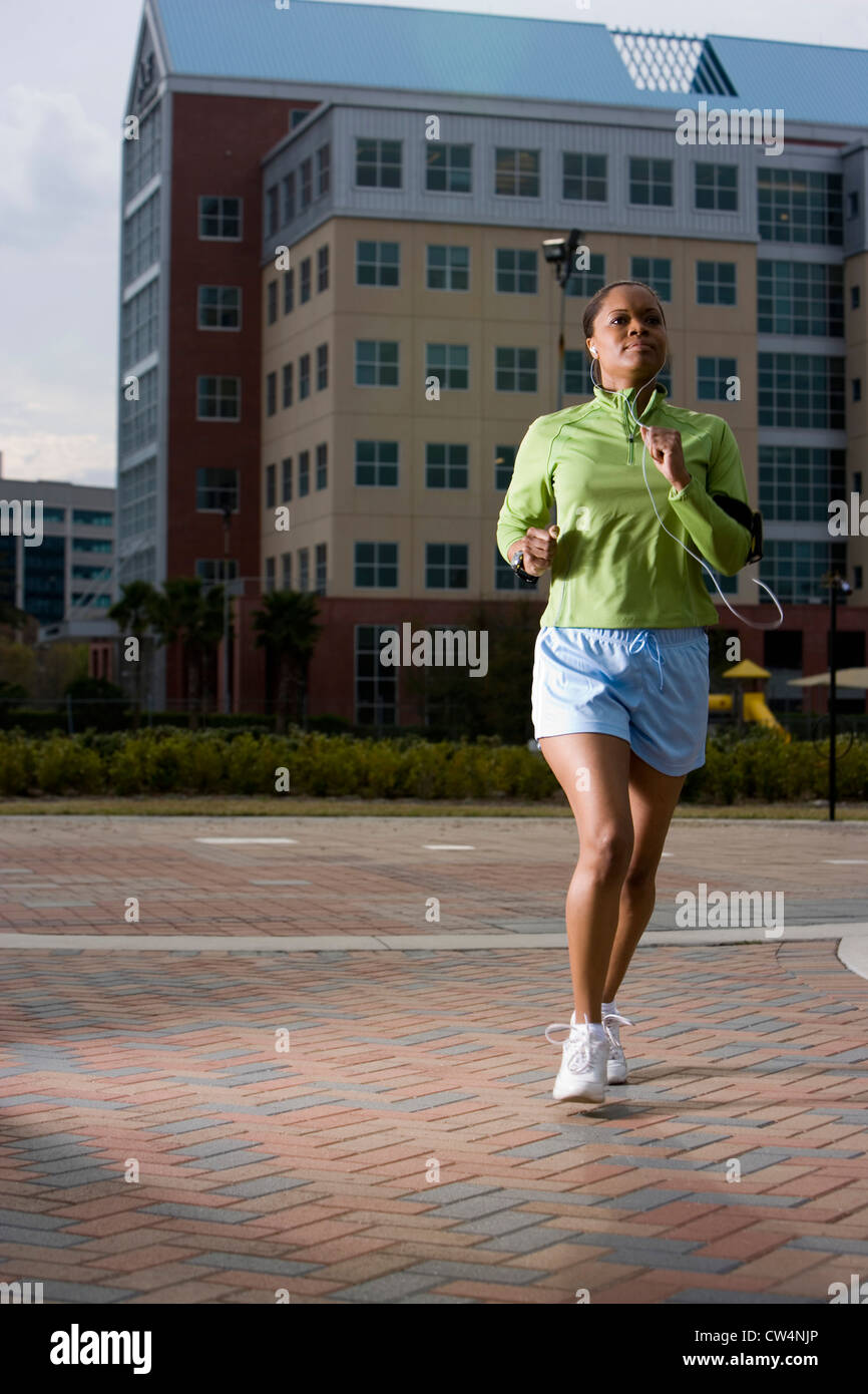 Young woman in sports clothing jogging on walkway with building in the ...