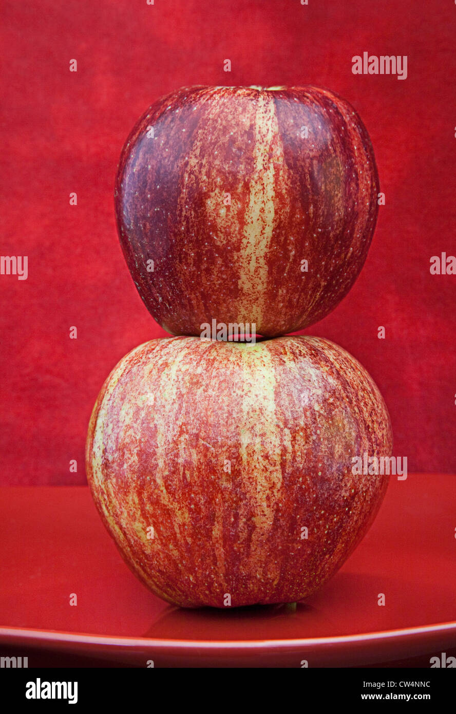One apple sitting on the top of another apple with a yellow stripe ...