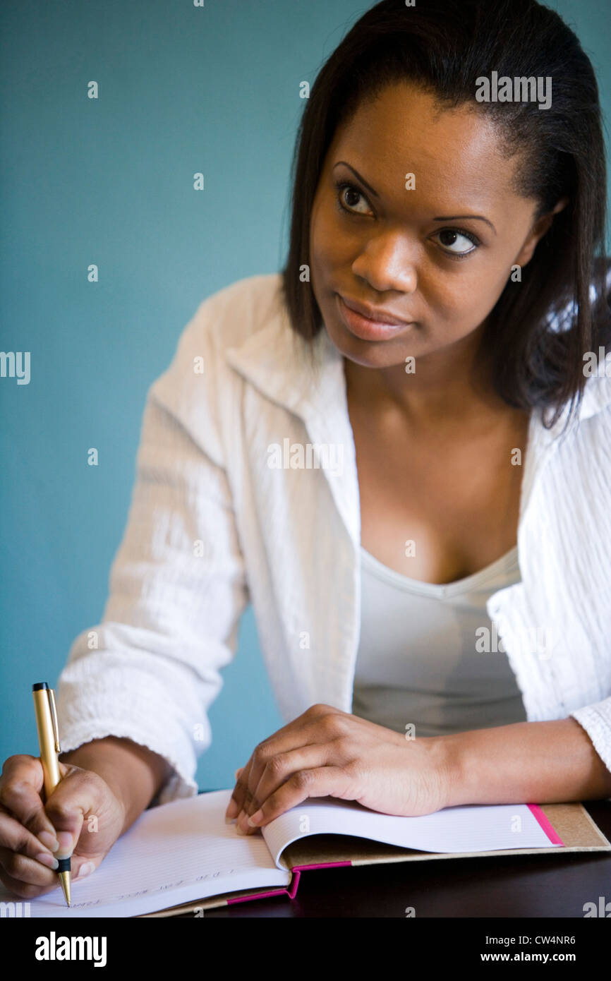 Contemplative young woman writing in a book Stock Photo - Alamy