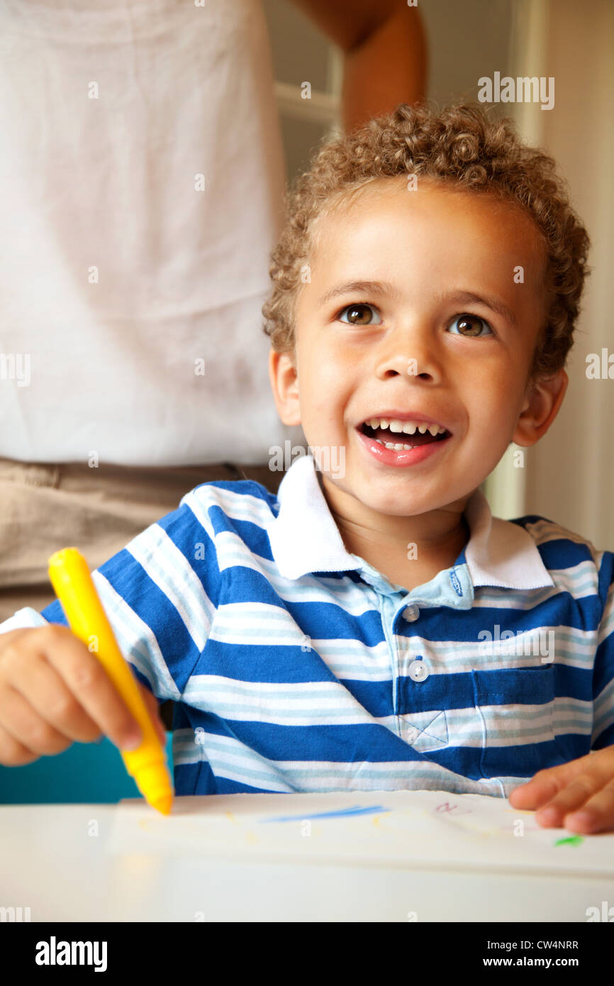 Preschooler looking happy and having fun while doing a coloring ...