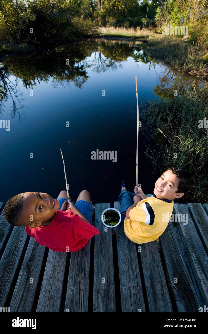 Portrait of cheerful friends fishing with fishing rods at the lake ...