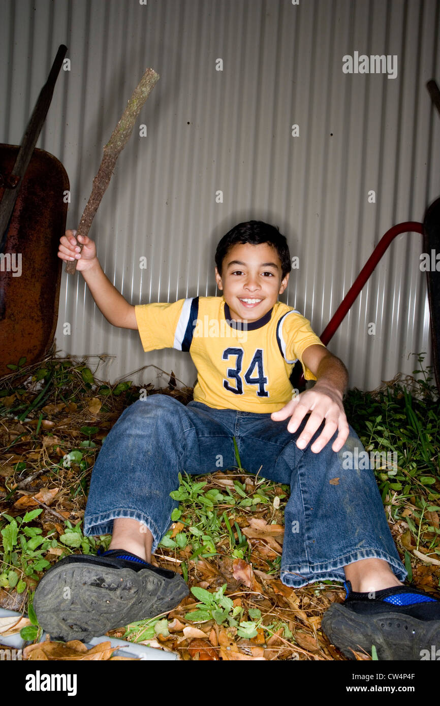 Portrait of a cheerful boy holding a stick by push cart Stock Photo - Alamy