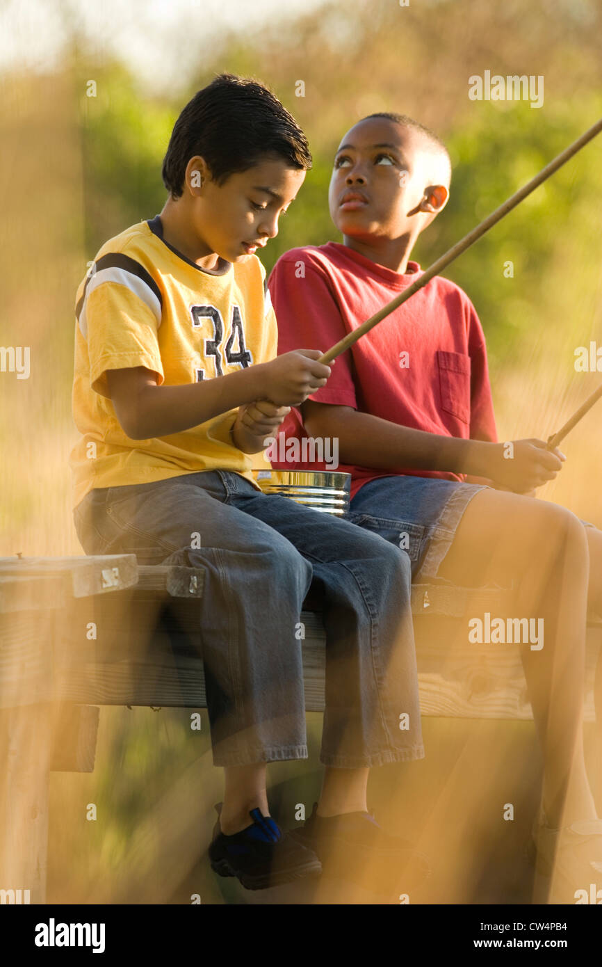 Friends fishing with fishing rods sitting on the jetty Stock Photo - Alamy