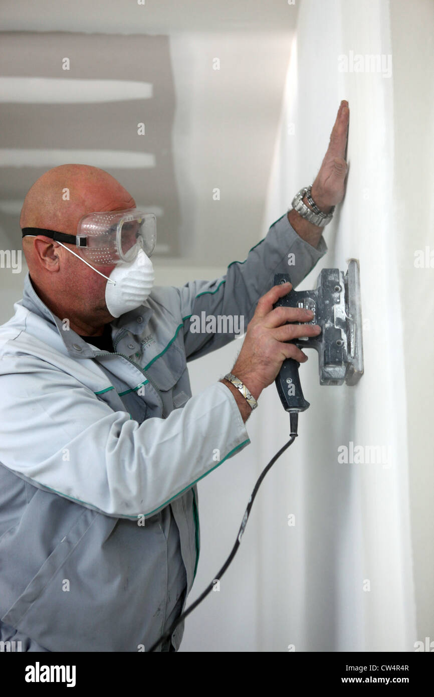 Man wearing mask and goggles whilst sanding wall Stock Photo - Alamy