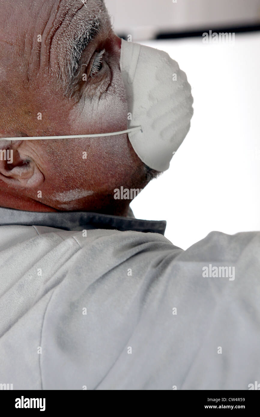 Man wearing face mask whilst sanding wall Stock Photo - Alamy