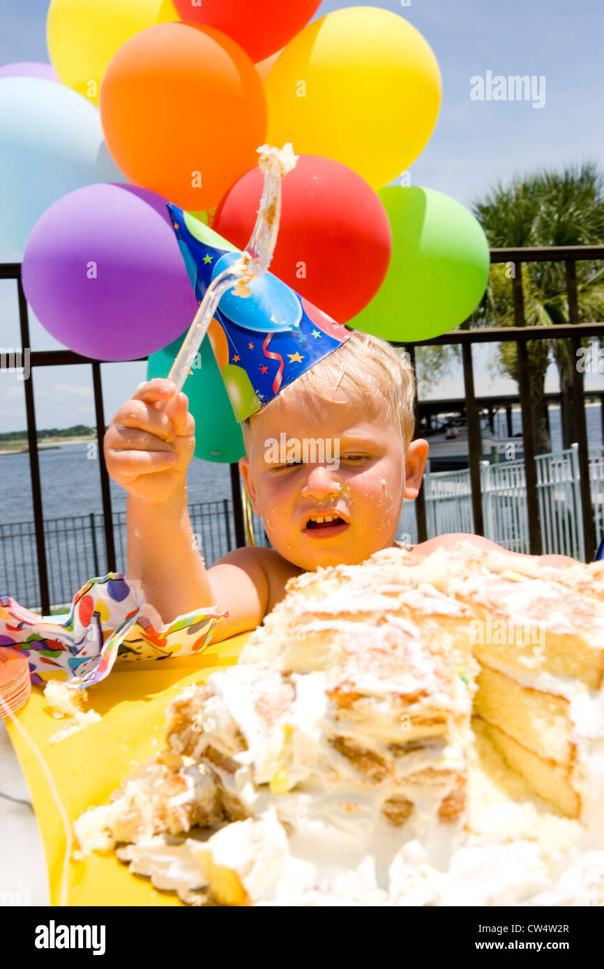 Boy holding balloons in front of a birthday cake Stock Photo - Alamy