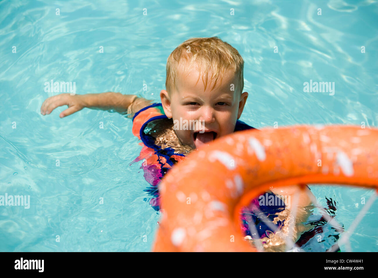 Portrait of a boy making a face and sticking out tongue in swimming ...