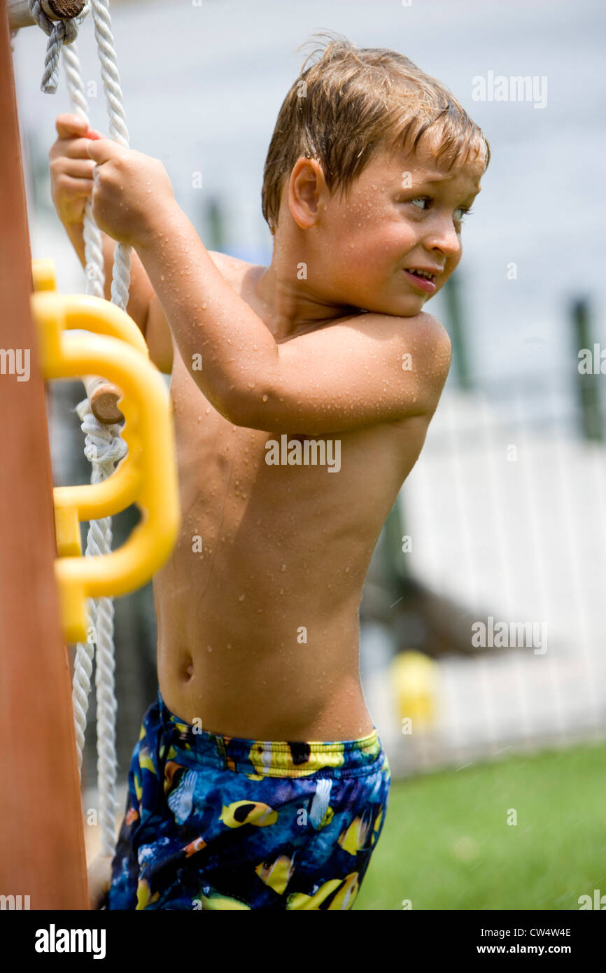 Boy climbing rope ladder and looking over shoulder Stock Photo - Alamy