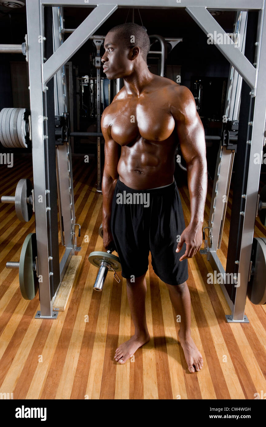 Shirtless young man standing in the gym and holding a dumbbell Stock ...