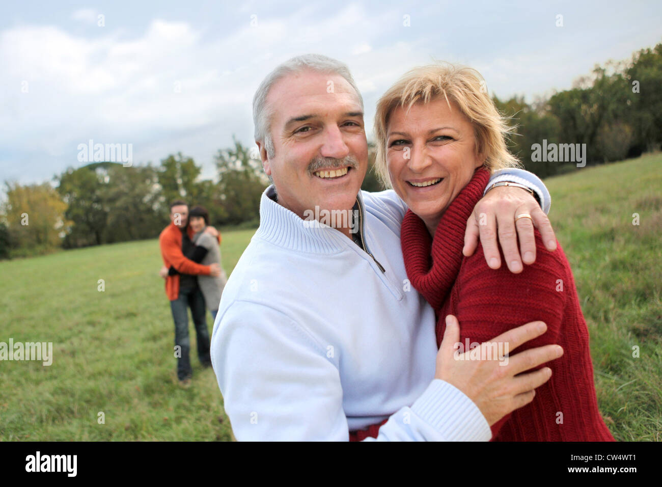 Couples hugging in a field Stock Photo - Alamy