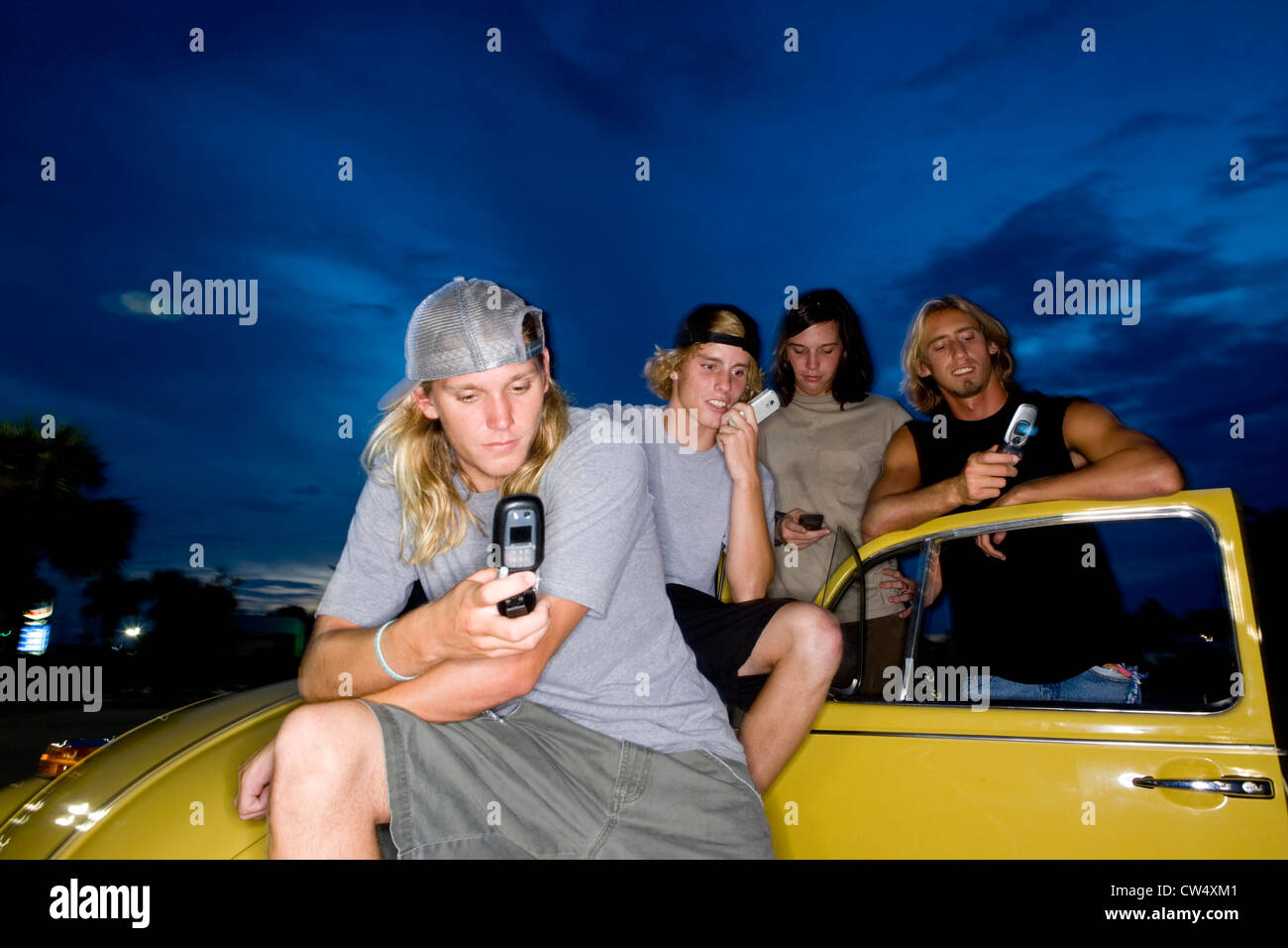 Friends using mobile phones by a car at the parking area Stock Photo ...