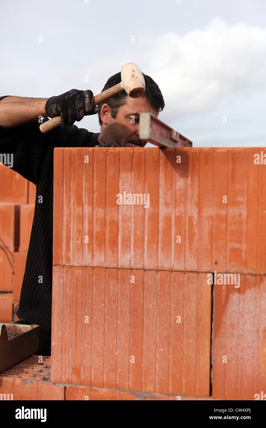 Mason using spirit-level to adjust angle of wall Stock Photo - Alamy