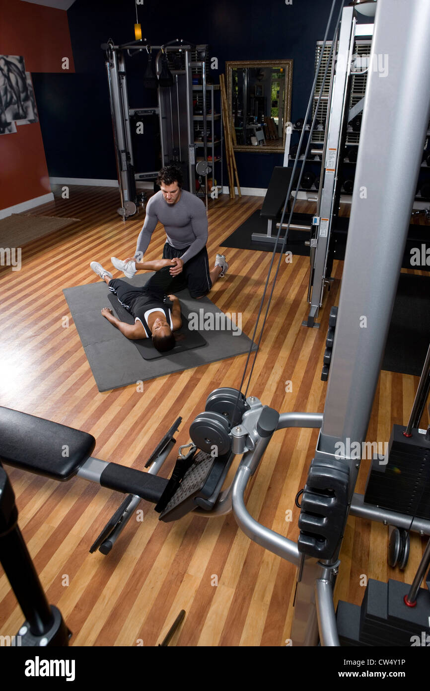 Trainer stretching leg of a young woman in the gym Stock Photo - Alamy
