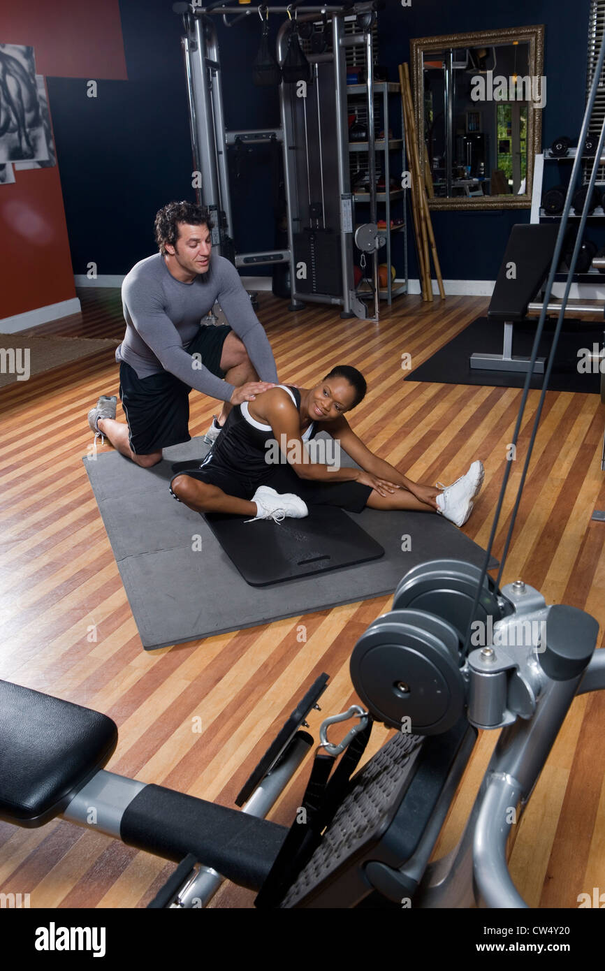 Trainer helping out of a young woman in the gym Stock Photo - Alamy