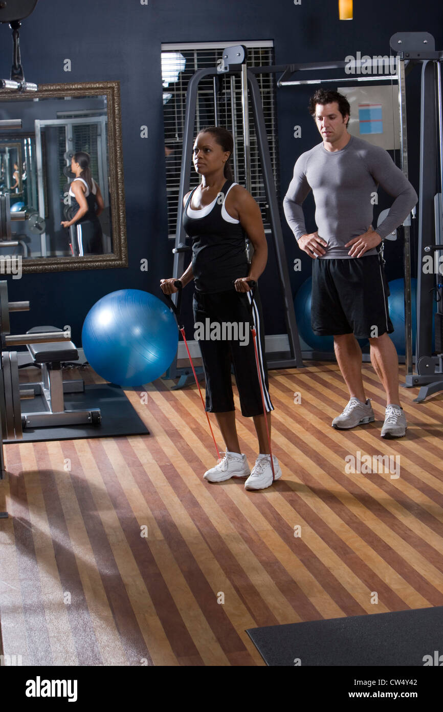 Trainer instructing a young woman in the gym Stock Photo - Alamy