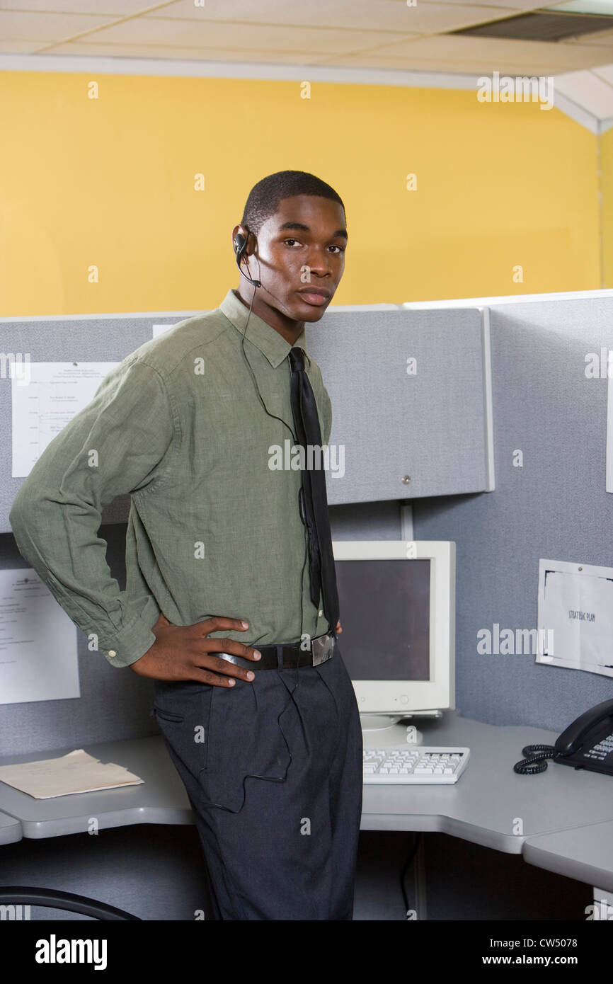 Portrait of a young man standing by a computer in an office Stock Photo ...