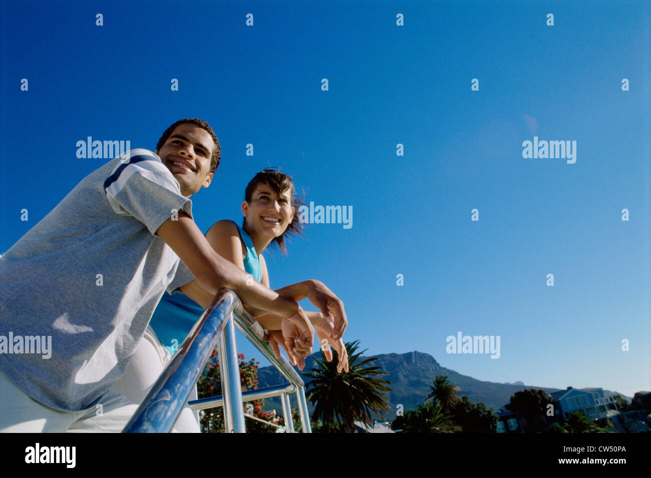 Low angle view of a young couple leaning against a railing Stock Photo ...
